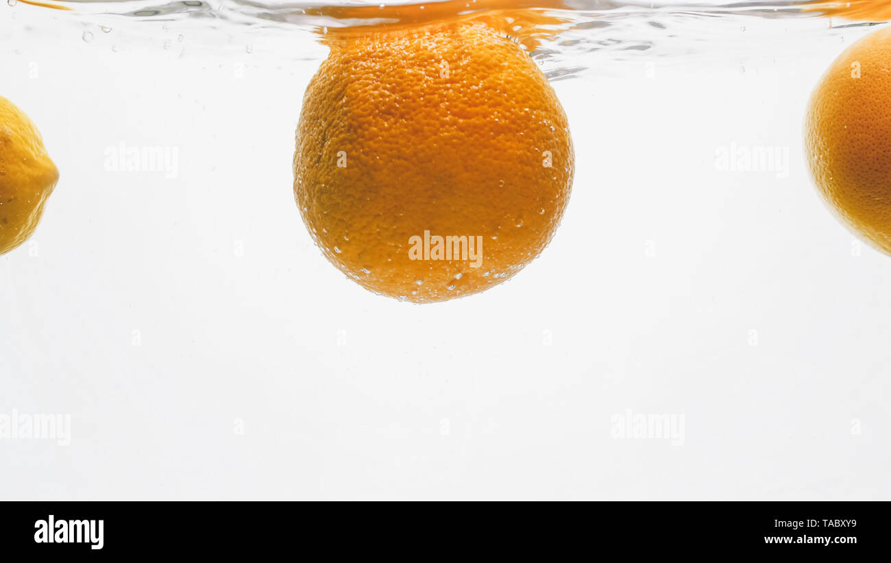 Closeup image of fresh juicy oranges falling in water. Tasty fruits ...