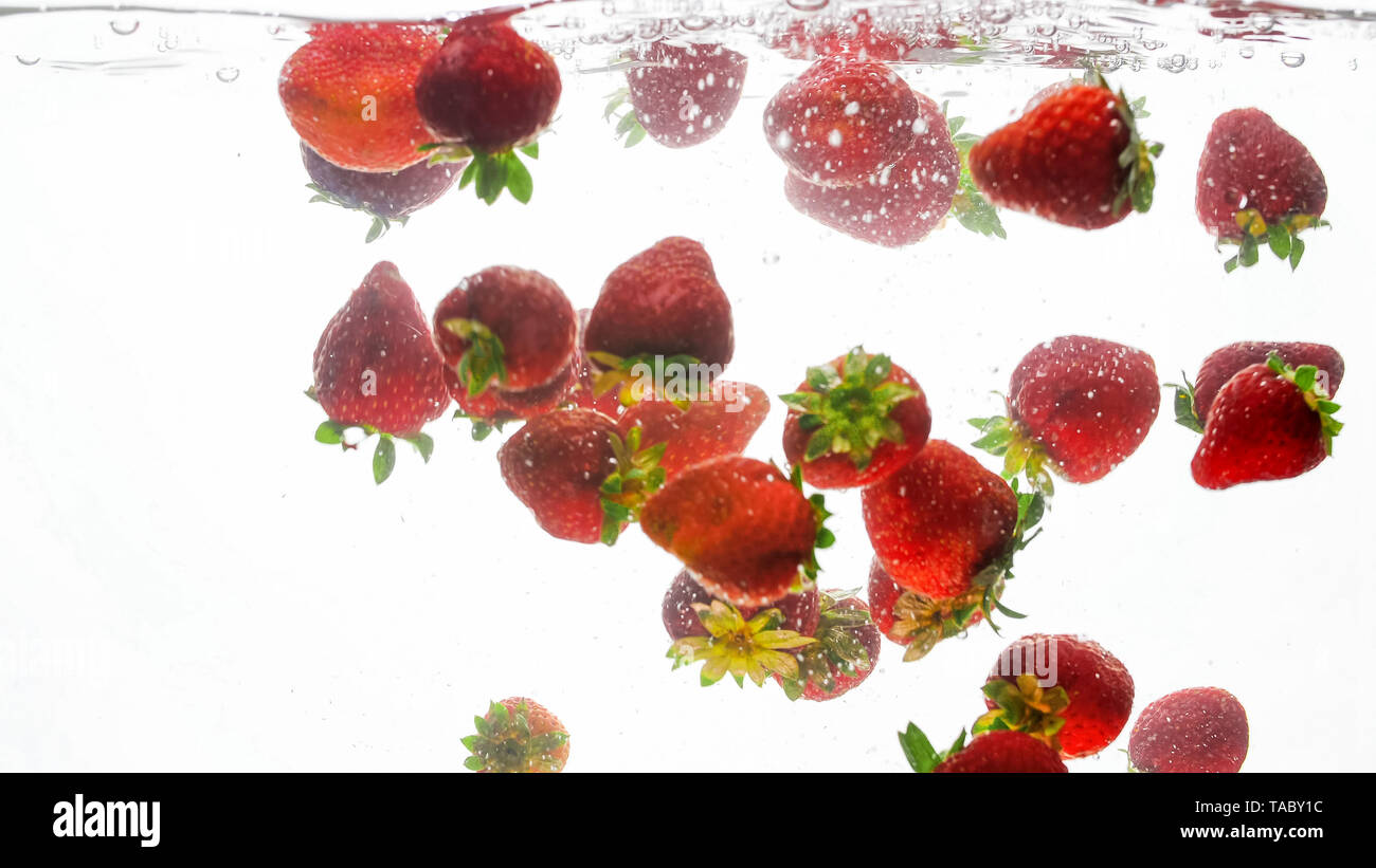 Closeup photo of lots of fresh ripe strawberries floating in clear ...