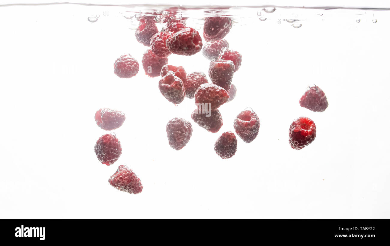 Closeup image of lots of fresh ripe tasty red raspberries flaoting with ...