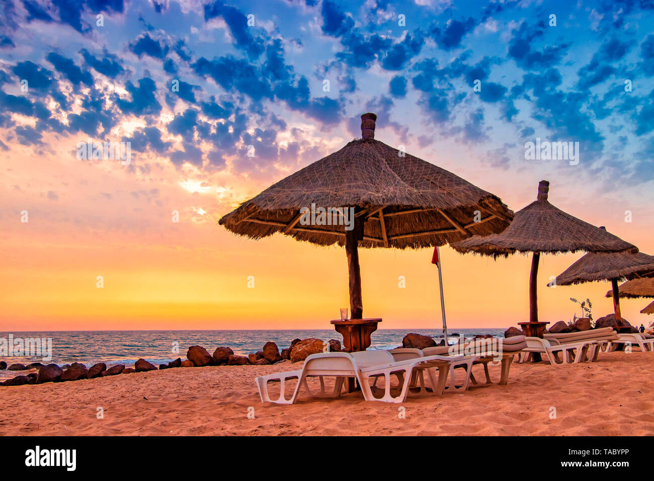 Deck chairs with umrellas on the beach with beautiful sunset in Senegal ...