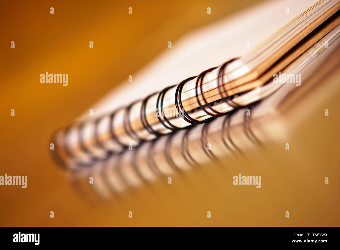 A clean notebook with a spring on a golden background. Work in the ...