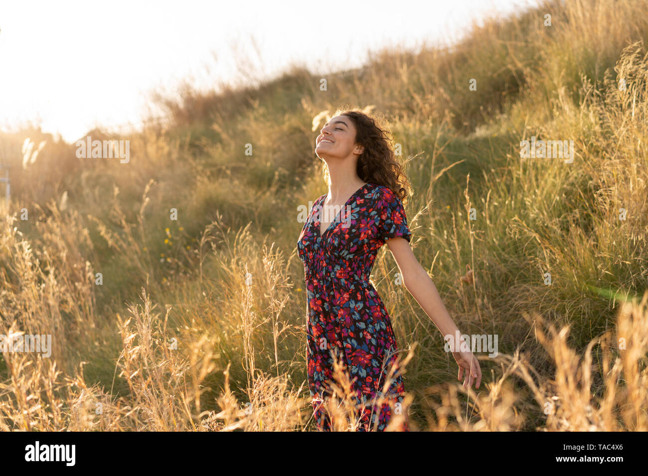 Happy young woman standing in summer meadow Stock Photo - Alamy