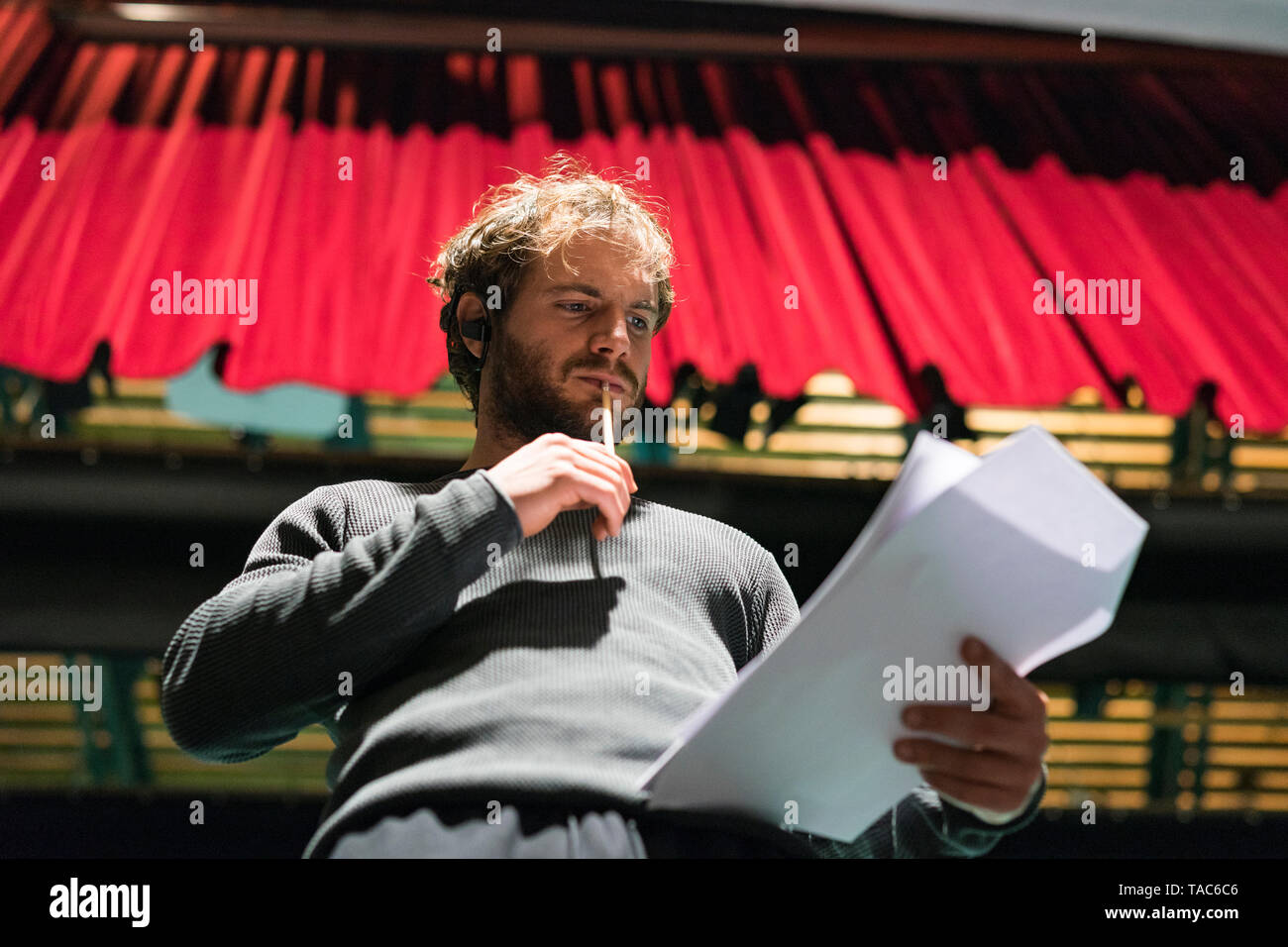 Portrait of pensive man standing on stage of theatre looking at script ...