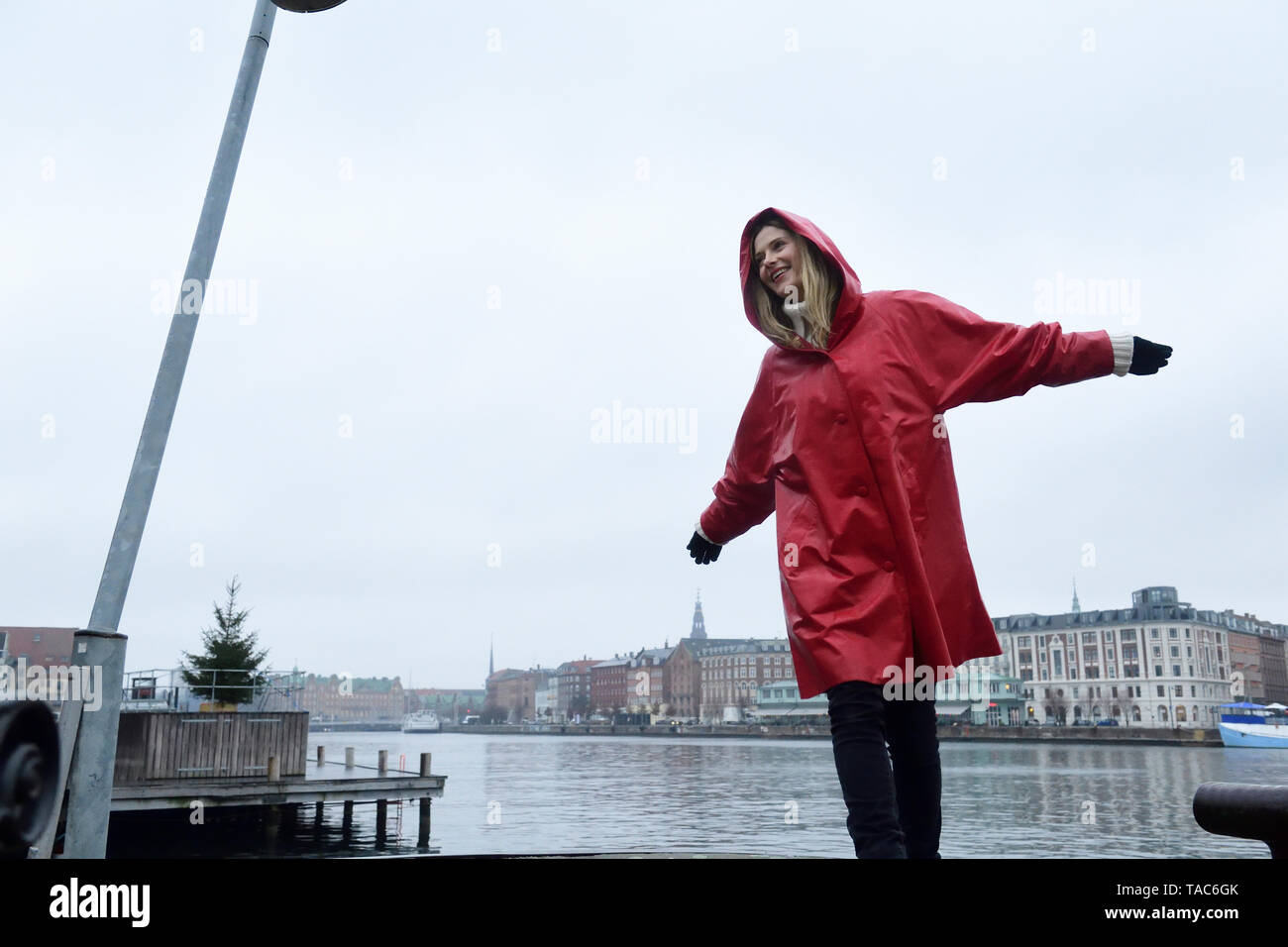 Denmark, Copenhagen, happy woman at the waterfront in rainy weather ...