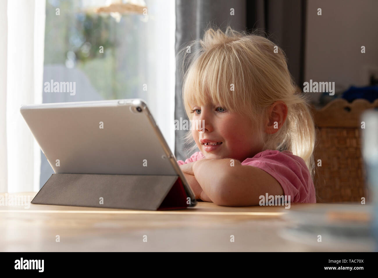 Portrait of blond little girl using digital tablet at home Stock Photo ...