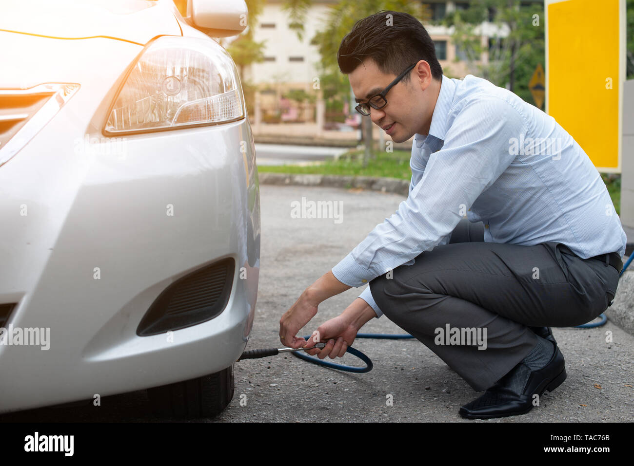 asian business man pumping air into car Stock Photo - Alamy
