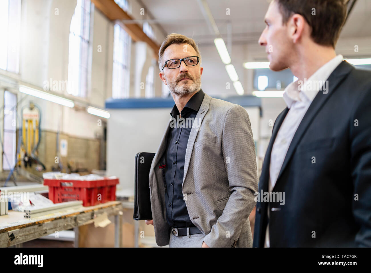 Two businessmen talking in a factory Stock Photo - Alamy