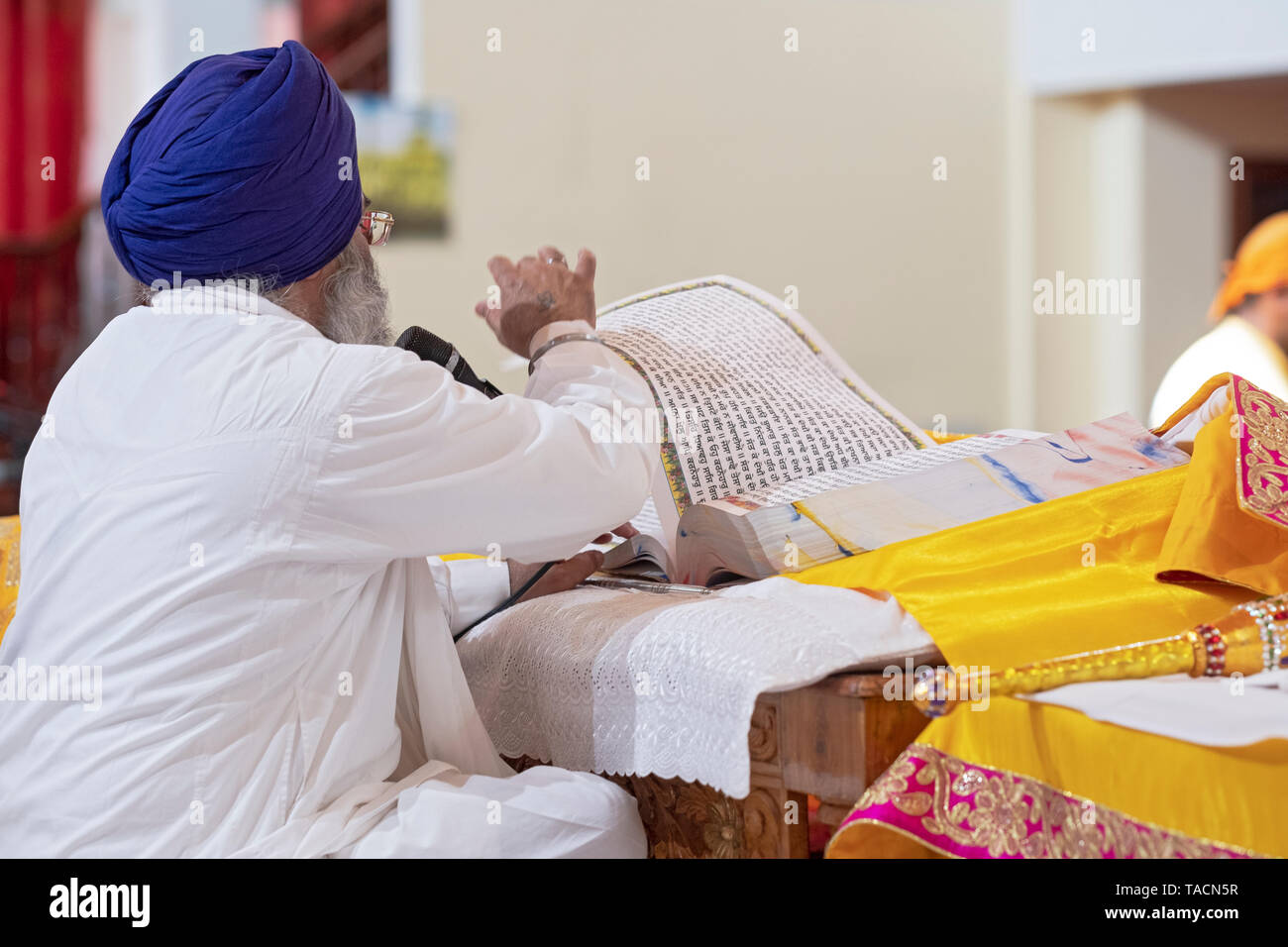 A Sikh priest in a turban reads from the holy book, the GURU GRANTH ...