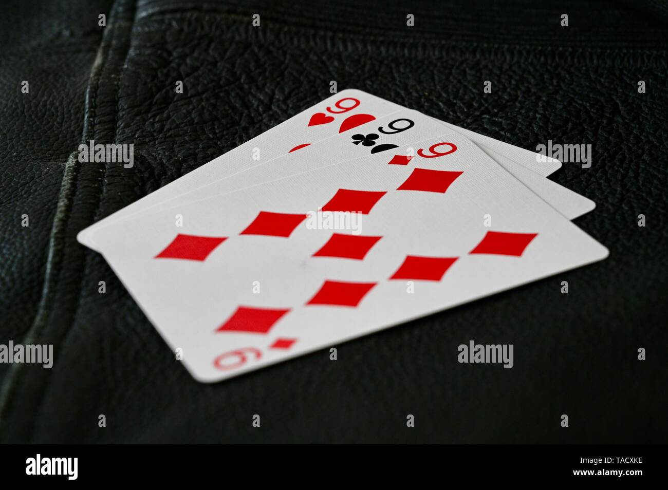 A fanned set of three nines, from a deck of cards, on a rich, textured ...