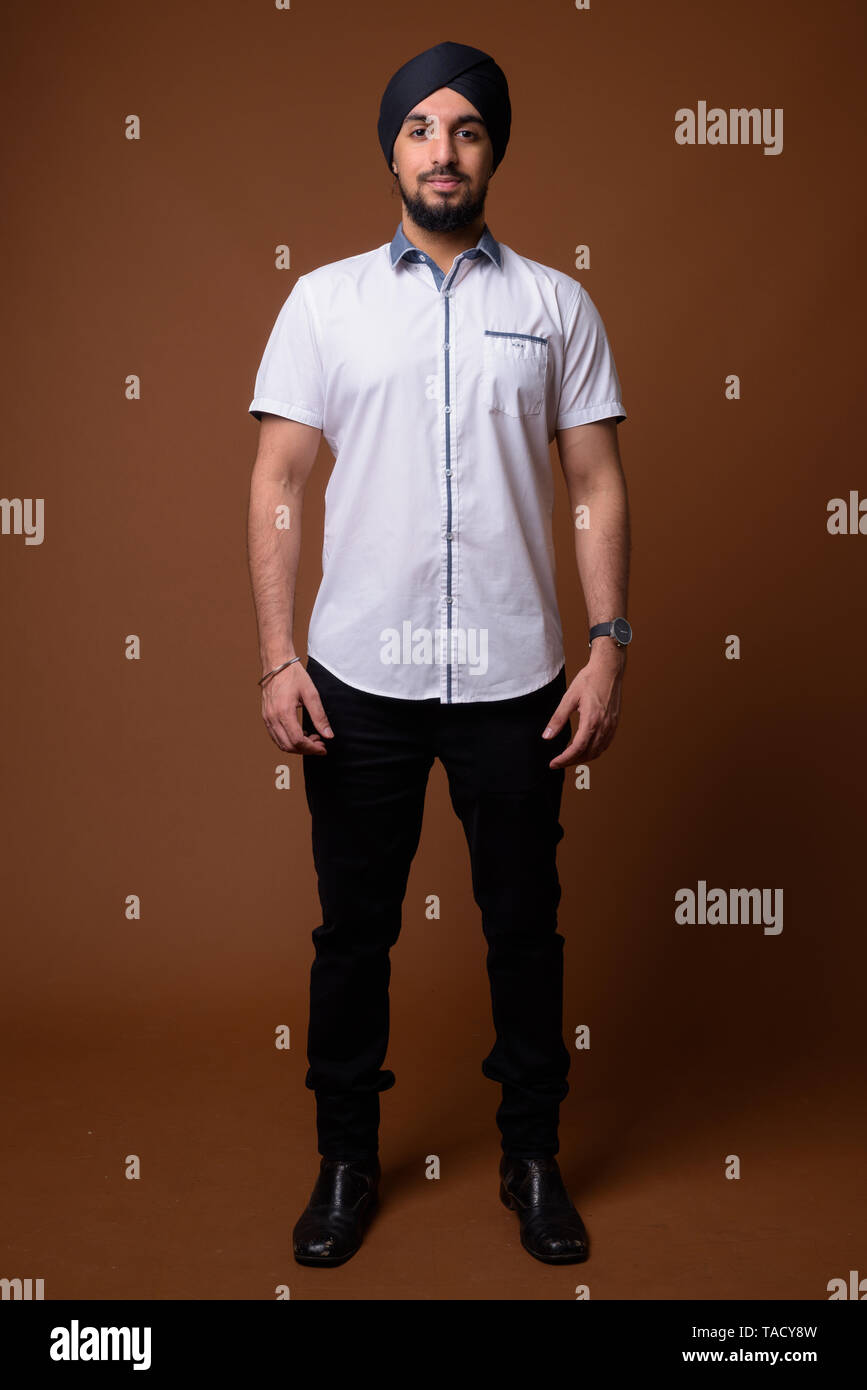 Studio shot of young bearded Indian Sikh man wearing smart casual ...