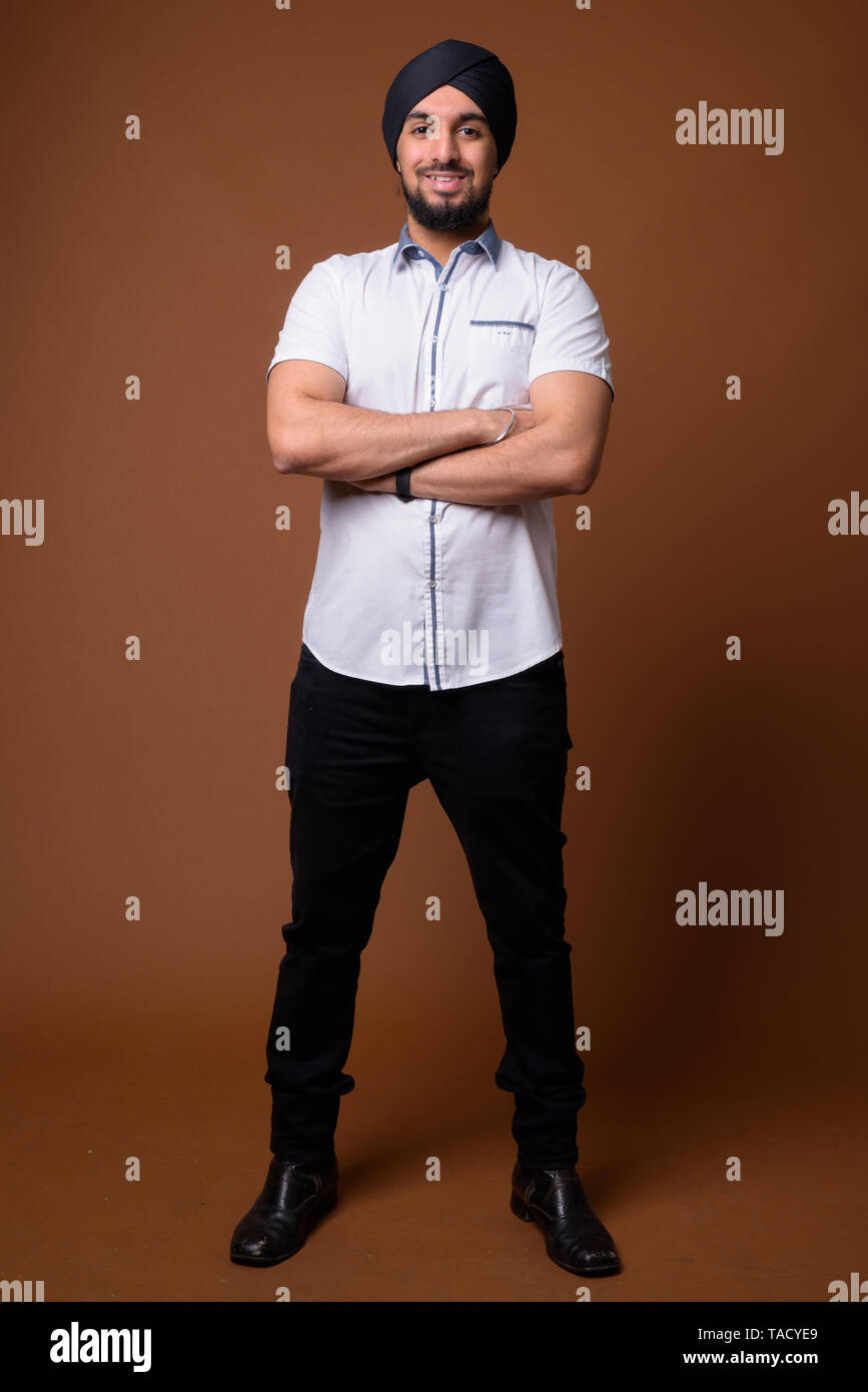 Studio shot of young bearded Indian Sikh man wearing smart casual ...