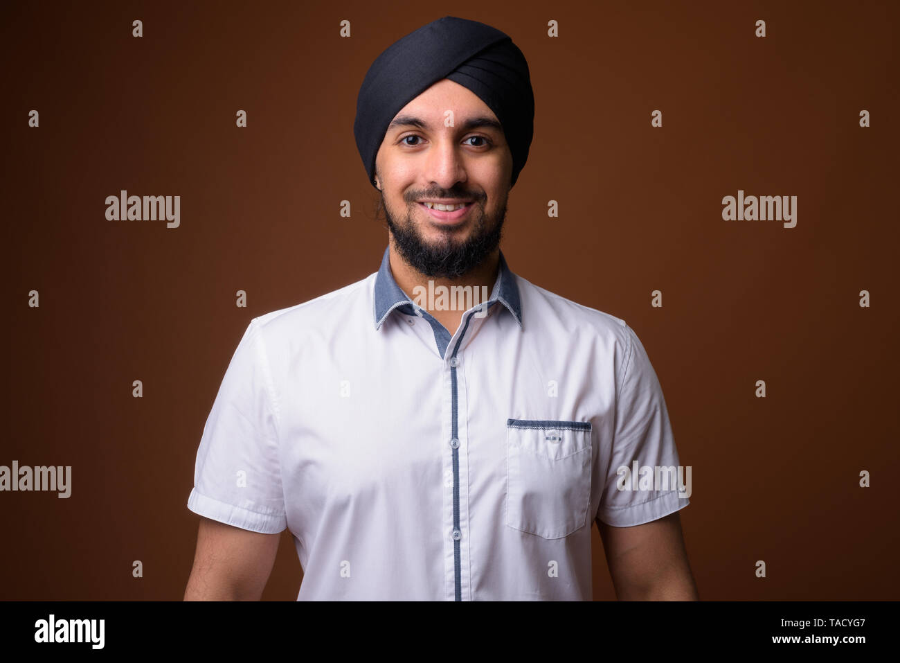 Studio shot of young bearded Indian Sikh man wearing smart casual ...