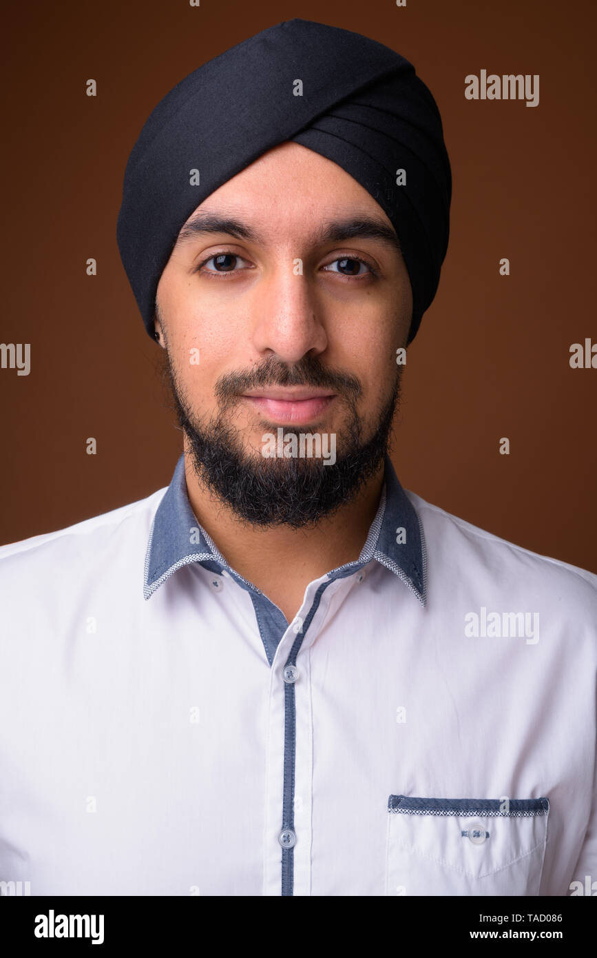 Studio shot of young bearded Indian Sikh man wearing smart casual ...