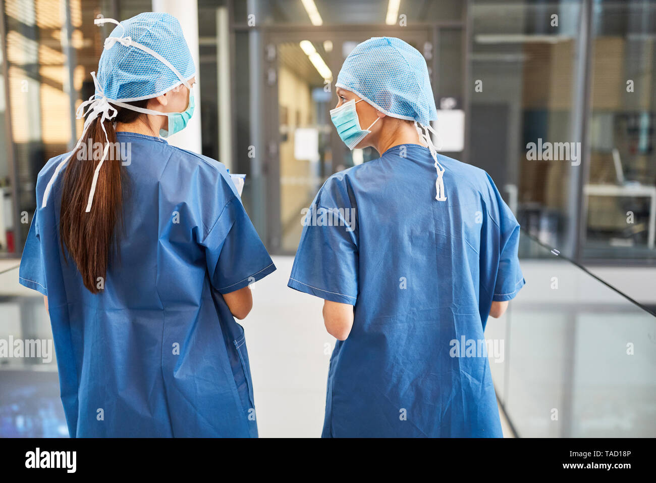 Two young women as surgeons in blue surgical clothing talking in the ...