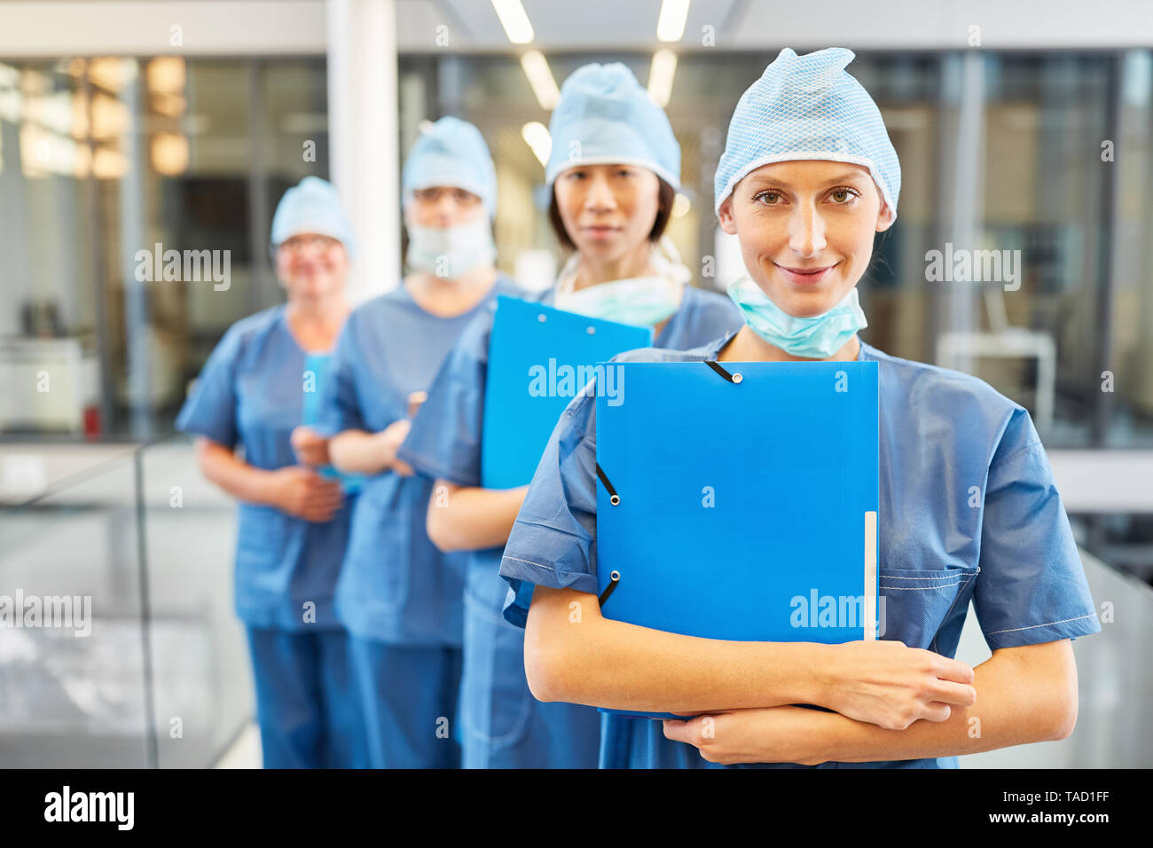Surgeons team with young female doctor or nurse in blue surgical ...