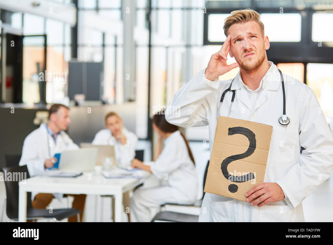 Young man as a doctor with question mark for decision and doubt in the ...