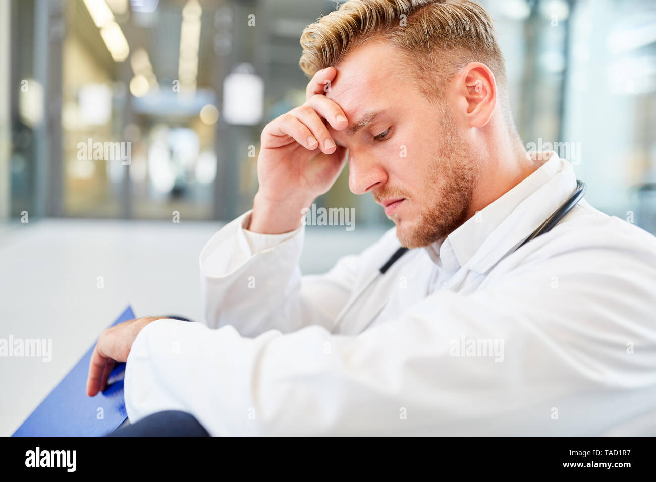 Young doctor sits exhausted in the hospital as a sign of overtime or ...