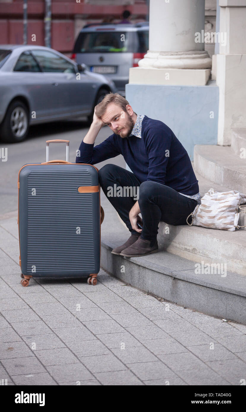 one young man, traveler or tourist, feeling lost and bored on a street ...