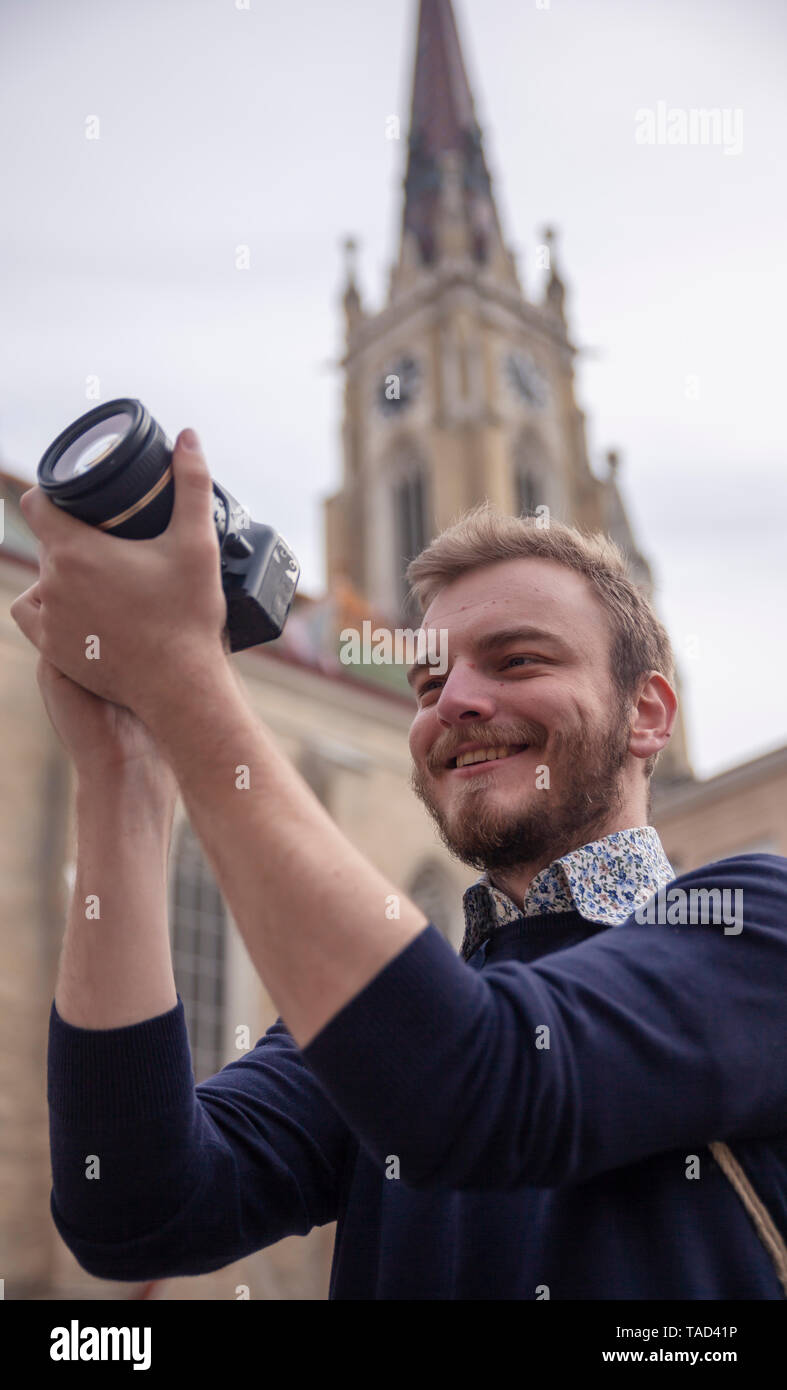 One young smiling man, tourist or traveler using a photo camera, in a ...