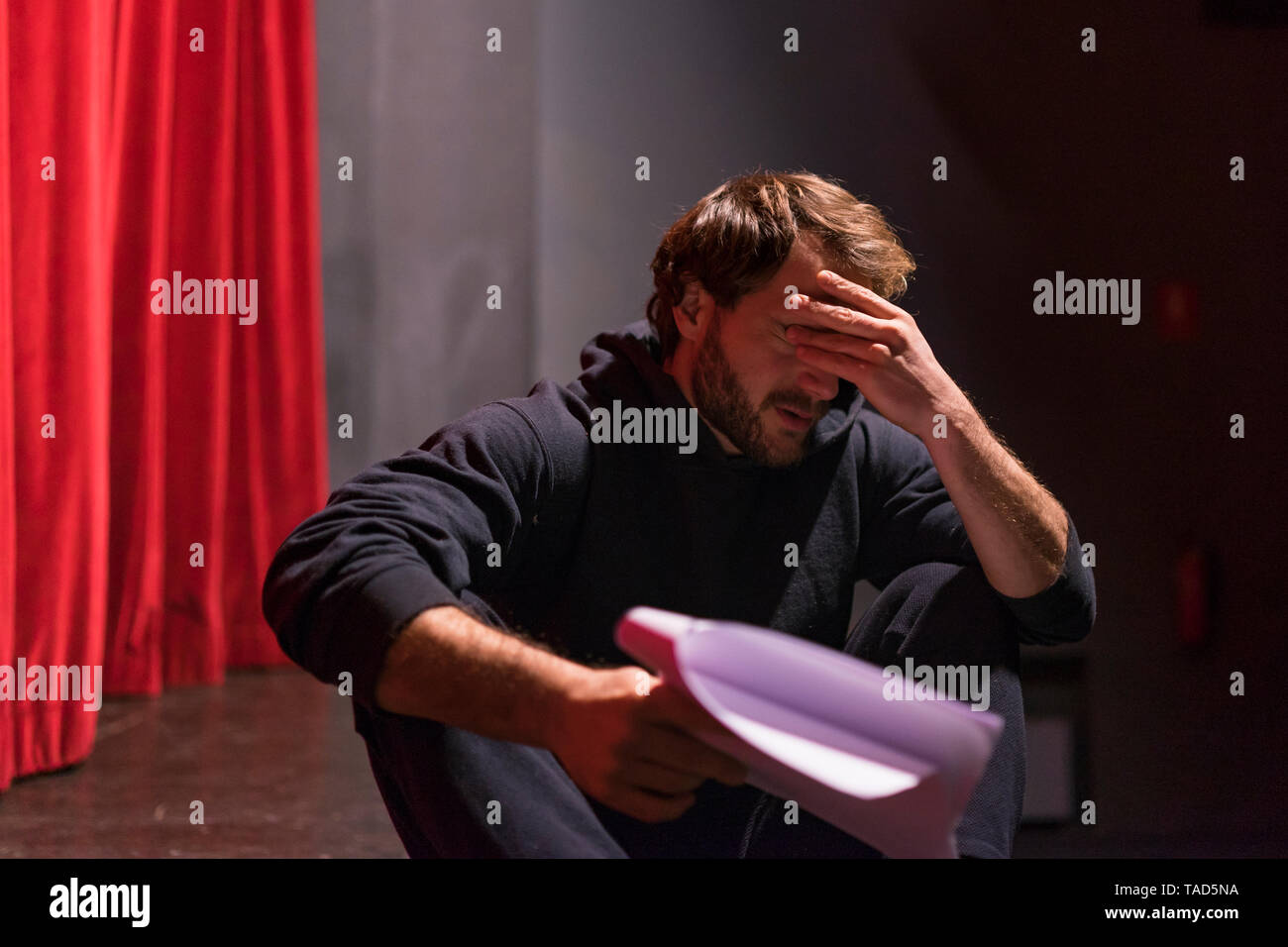 Rehearsing actor sitting on stage of theatre with script Stock Photo ...
