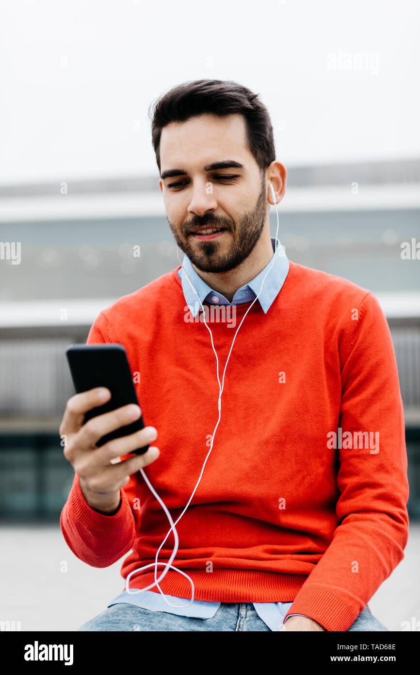 Using his smartohone and earphones hi-res stock photography and images ...