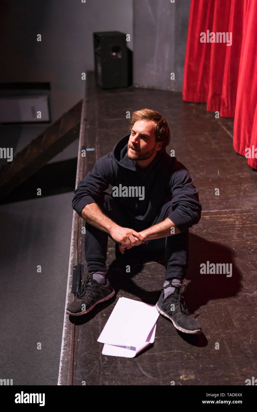 Rehearsing actor sitting on stage of theatre with script Stock Photo ...