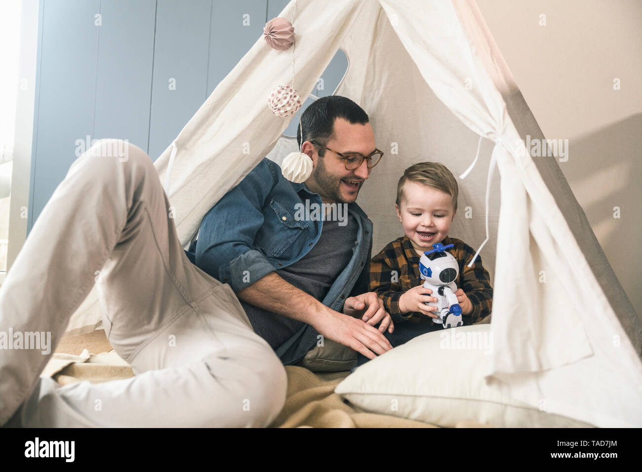 Happy father and son playing with a robot in tent at home Stock Photo ...