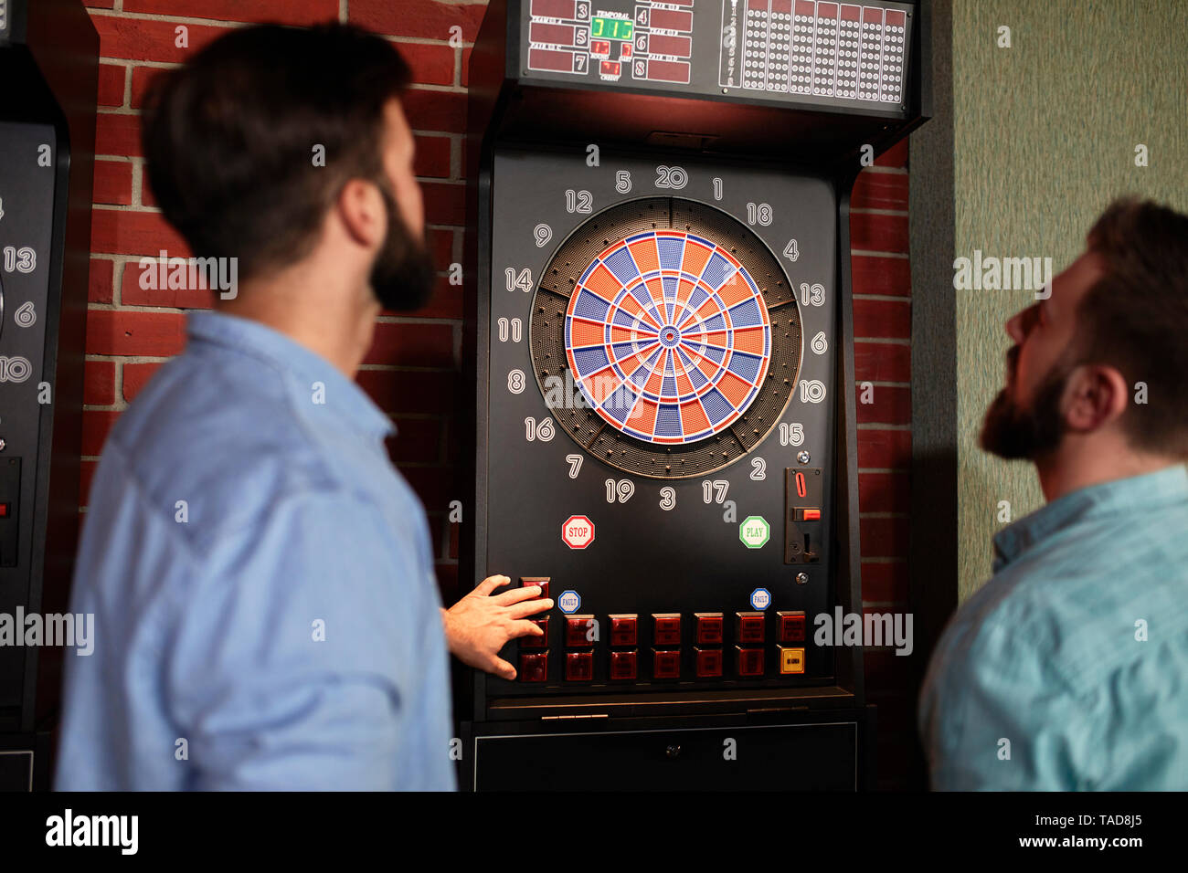 Two men playing darts setting electronic dartboard Stock Photo - Alamy