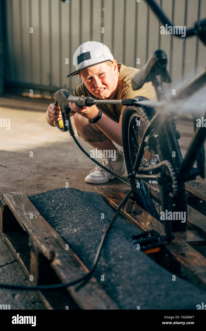 Boy washing bmx bike with pressure washer on yard Stock Photo - Alamy