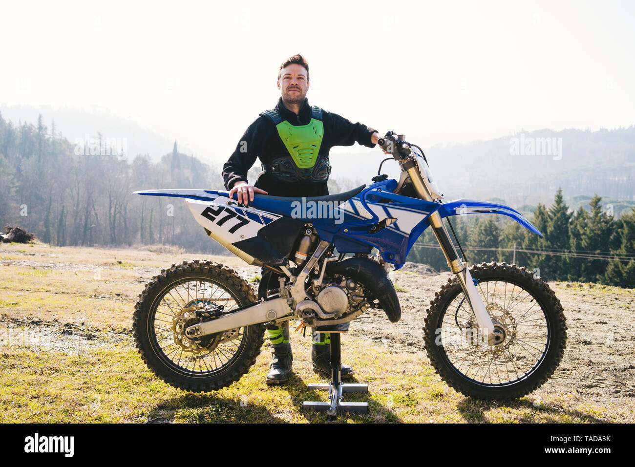 Motocross driver with jacked up motorbike Stock Photo - Alamy