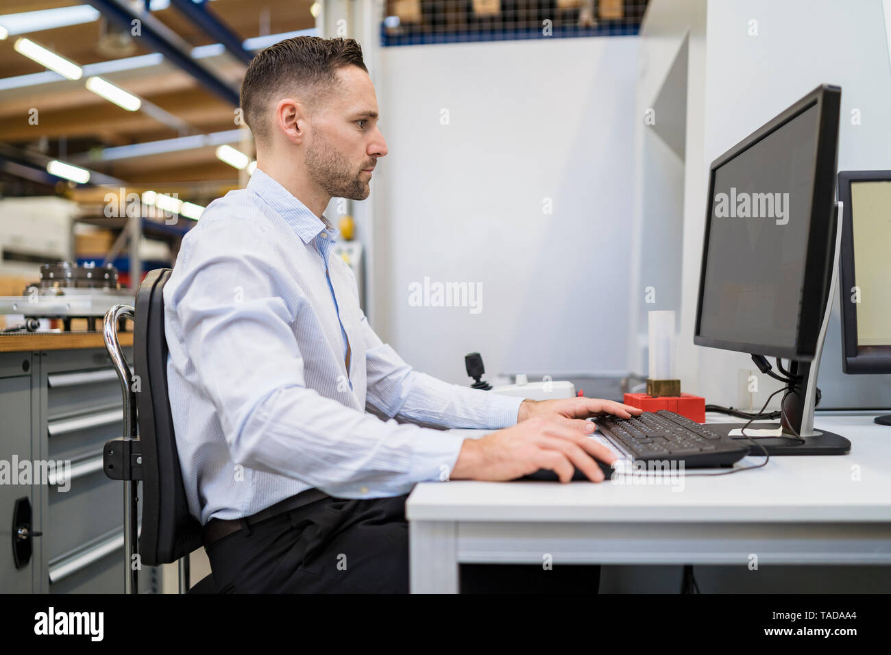 Businessman using computer at desk in a factory Stock Photo - Alamy