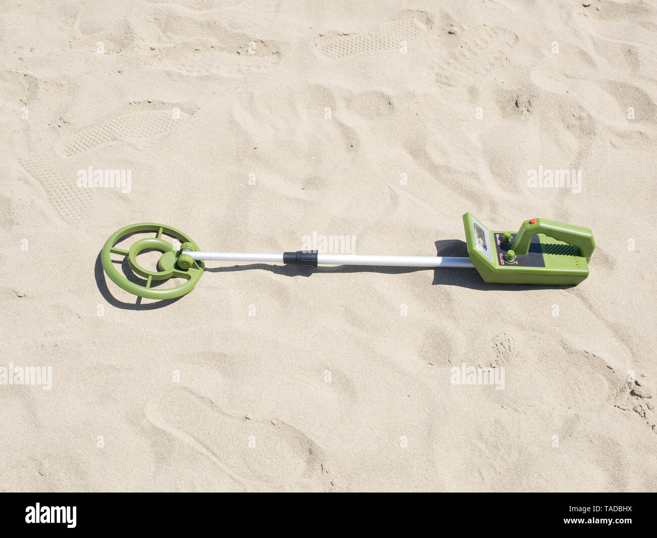 green toy metal detector on a fine sandy beach ready for searching ...