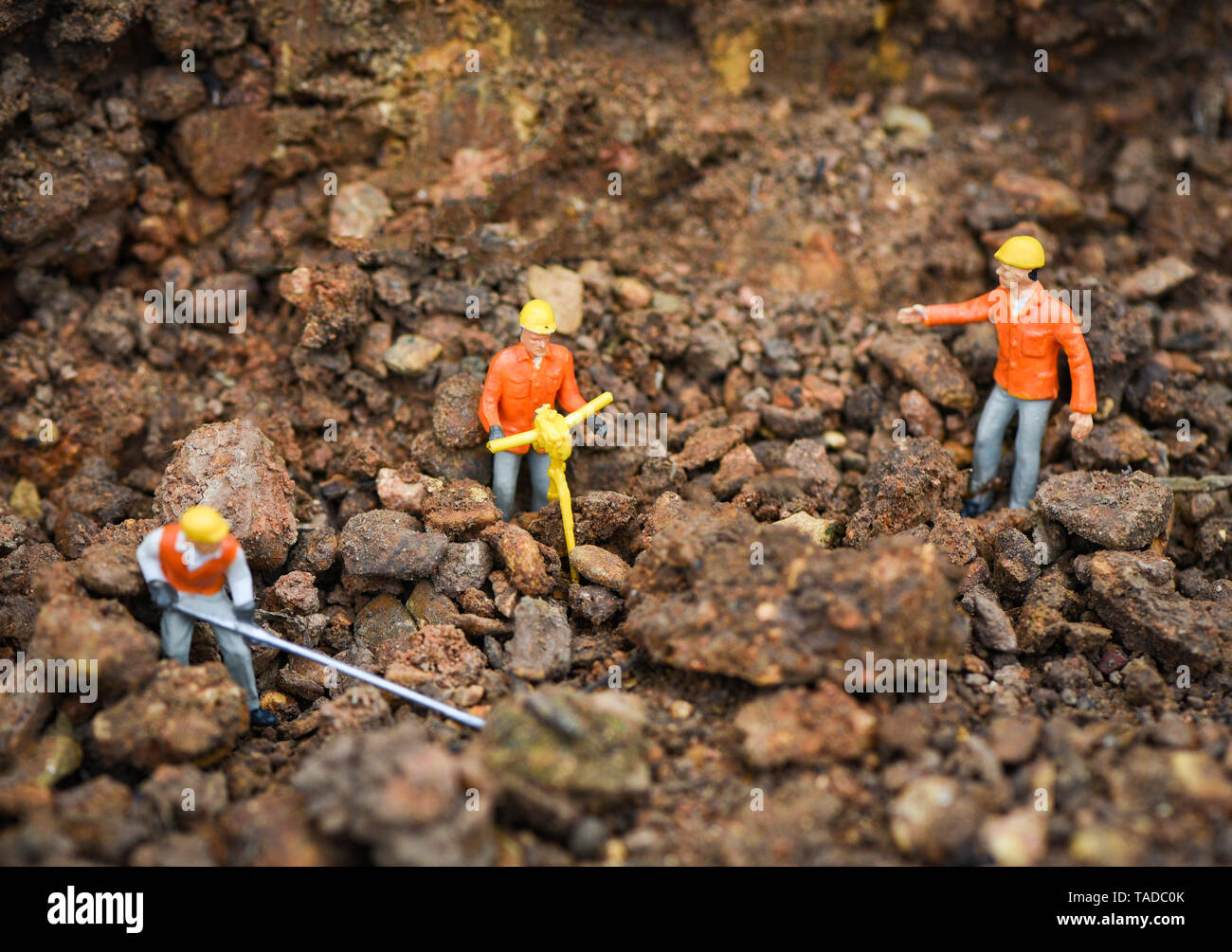 Construction worker concept / figurines working digging ground soil ...