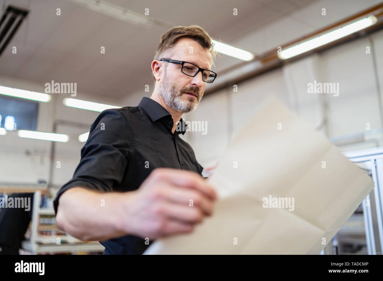 Man in factory holding plan Stock Photo - Alamy