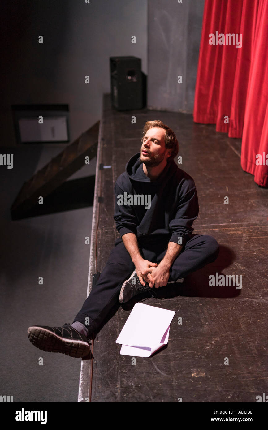 Rehearsing actor sitting on stage of theatre with script Stock Photo ...