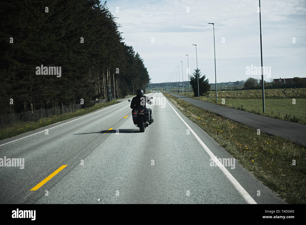 Back view of biker in black leather jacket and helmet riding motorcycle ...