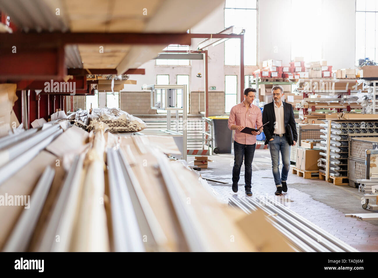 Two men walking in factory warehouse Stock Photo - Alamy