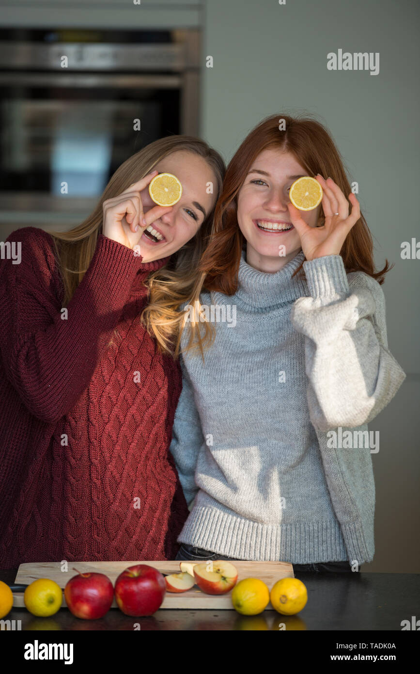 Two laughing friends holding lemon halves in front of their eyes Stock ...
