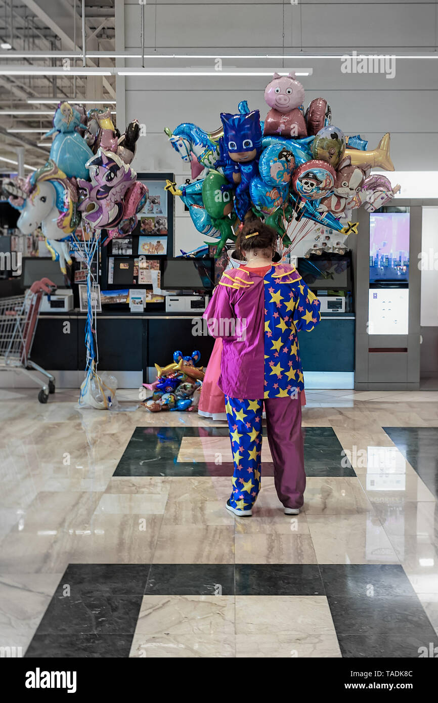 A clown is selling balloons in a bunch at a shopping center in Serris ...