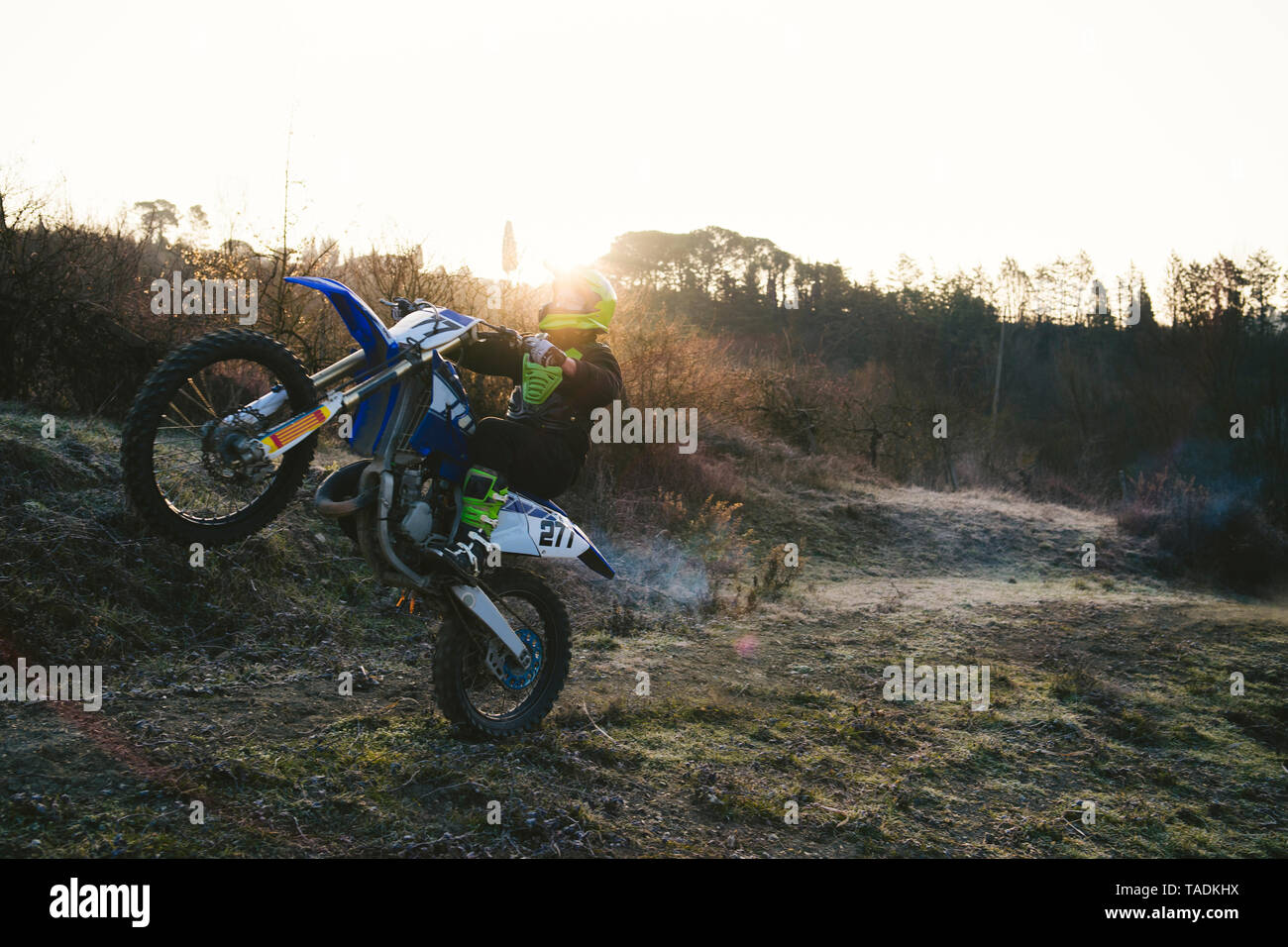 Motocross driver riding on circuit doing a wheelie Stock Photo - Alamy