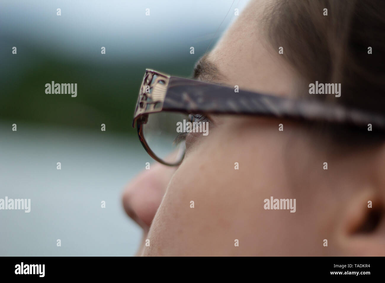 Girl staring into distance with glasses Stock Photo - Alamy