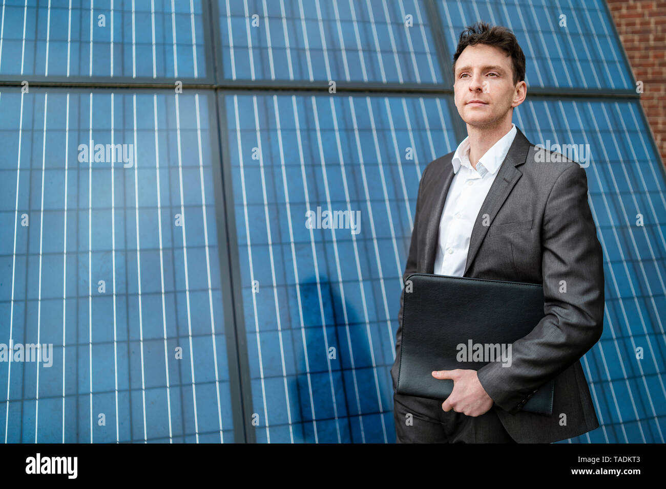 Businessman holding folder standing in front of solar panels Stock ...