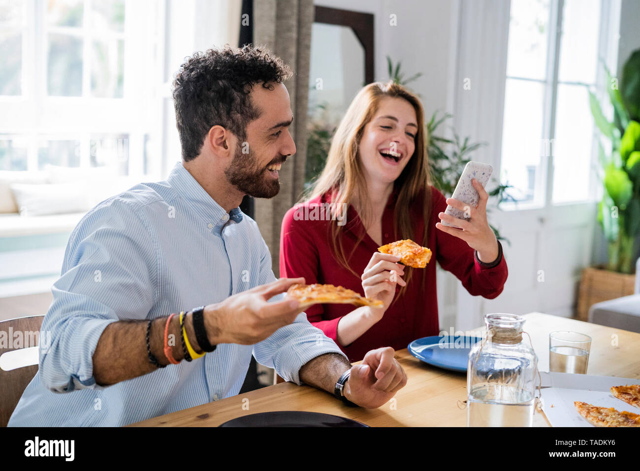 Friends having fun, eating pizza, using smartphone Stock Photo - Alamy