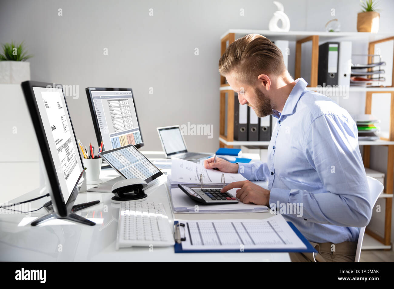 Businessperson Calculating Invoice With Computer On Desk Stock Photo ...