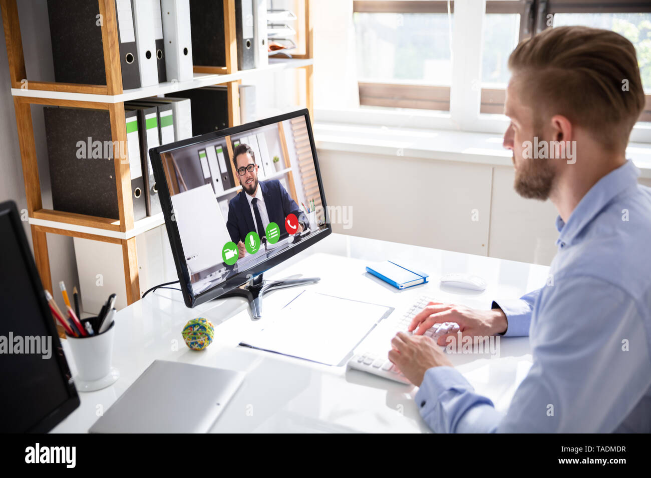 Side view of businessman video conferencing with coworker on desktop PC ...