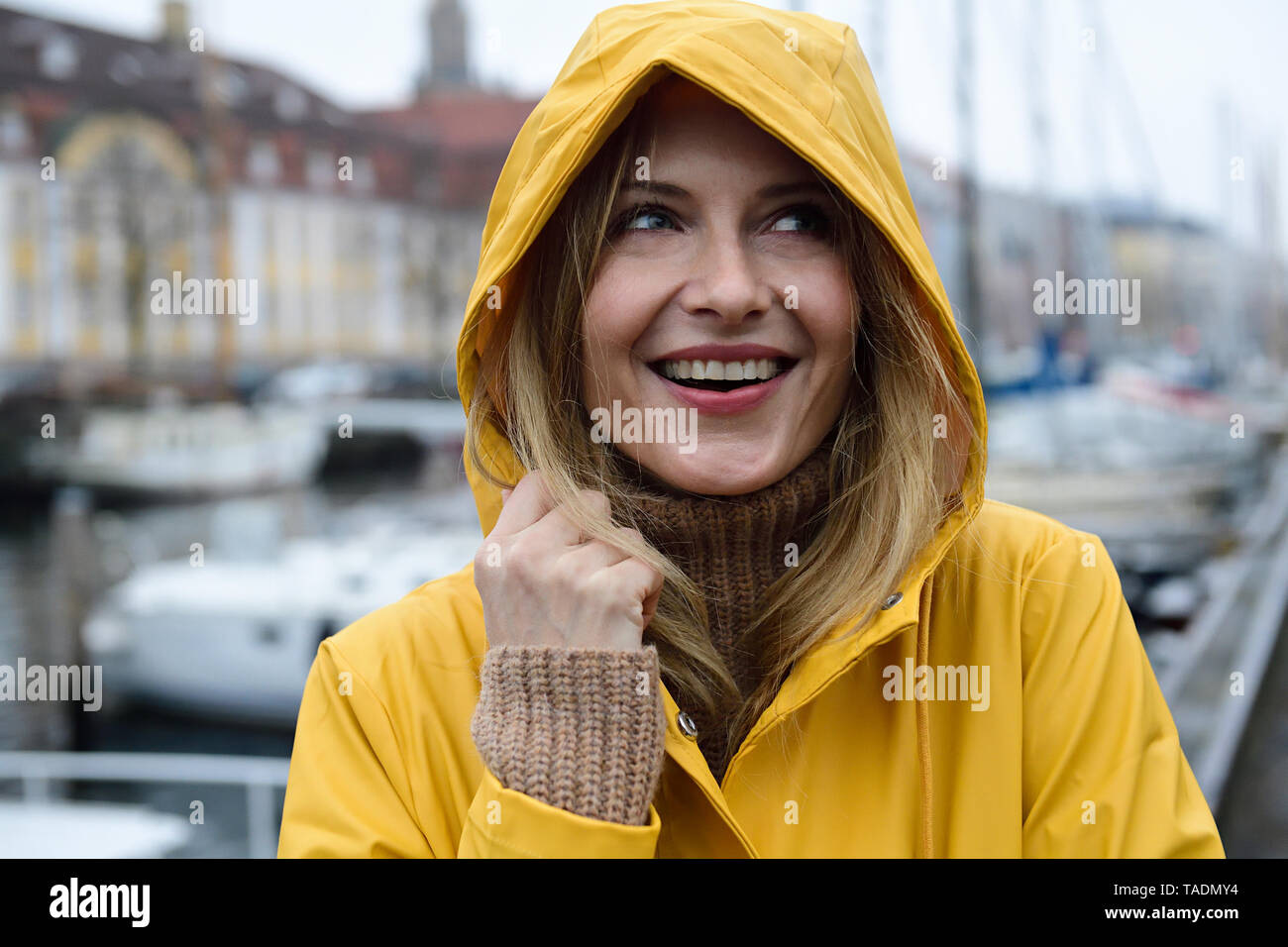 Denmark, Copenhagen, portrait of happy woman at city harbour in rainy ...