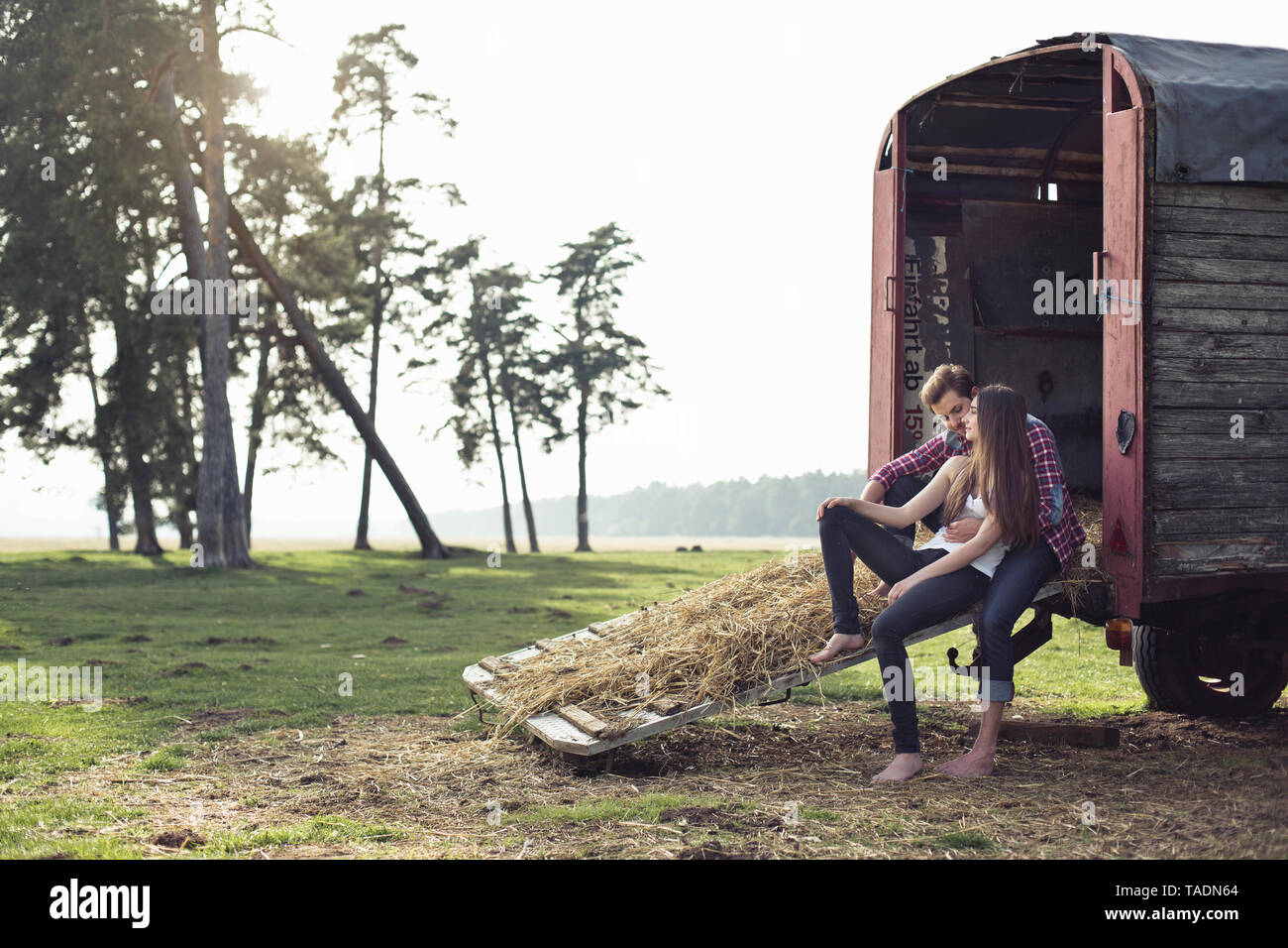 Happy young couple sitting on trailer in the countryside Stock Photo ...