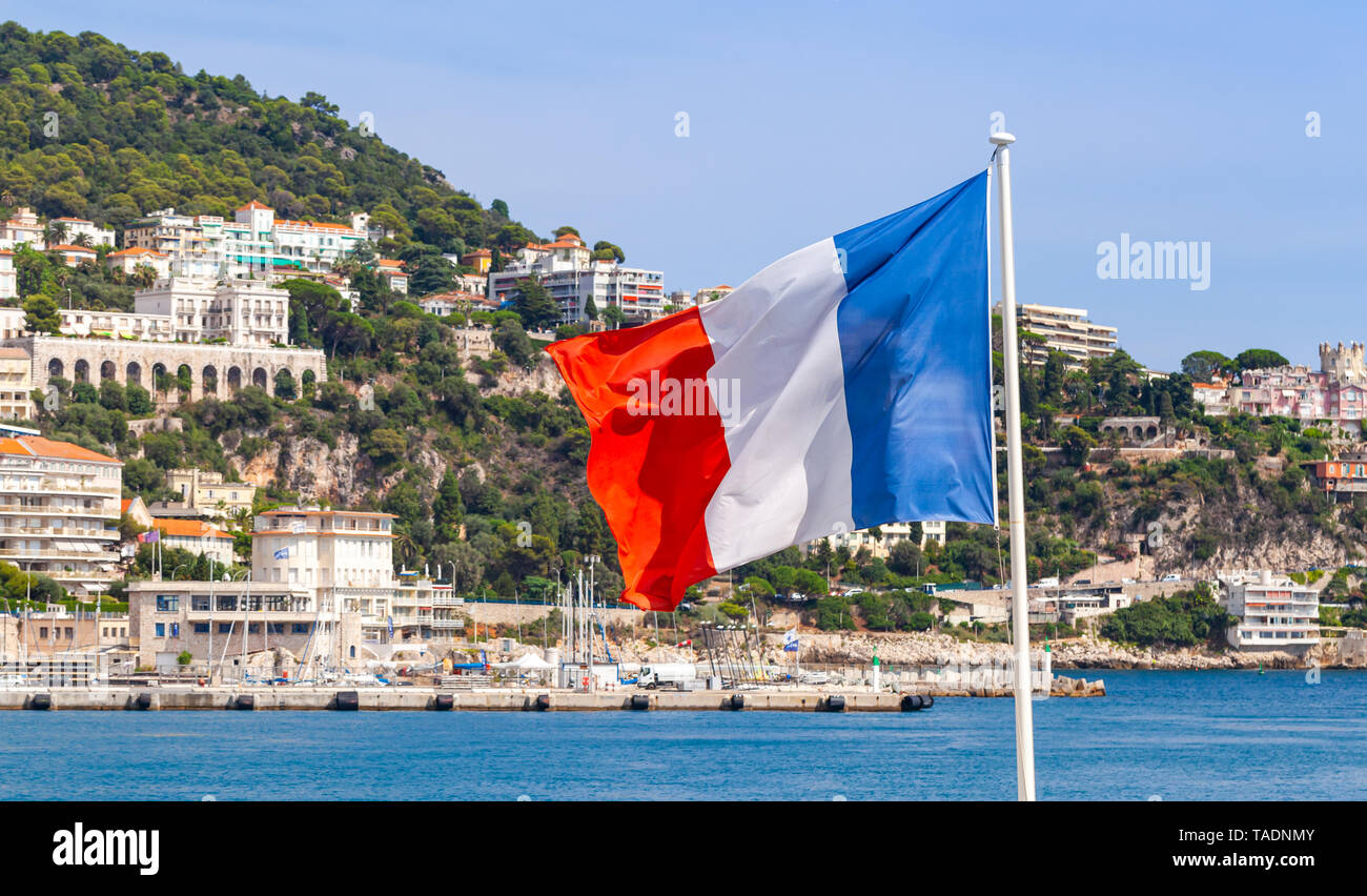 Flag of France waving on wind over blurred coastal landscape background ...