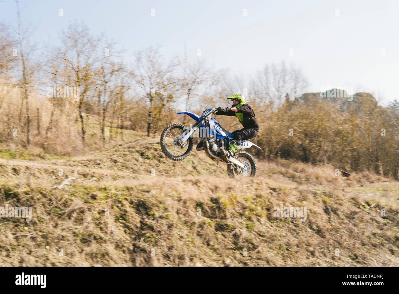 Motocross driver riding on circuit doing a wheelie Stock Photo - Alamy