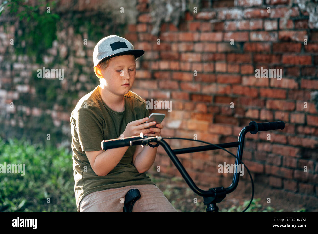 Boy with bmx bike using cell phone Stock Photo - Alamy